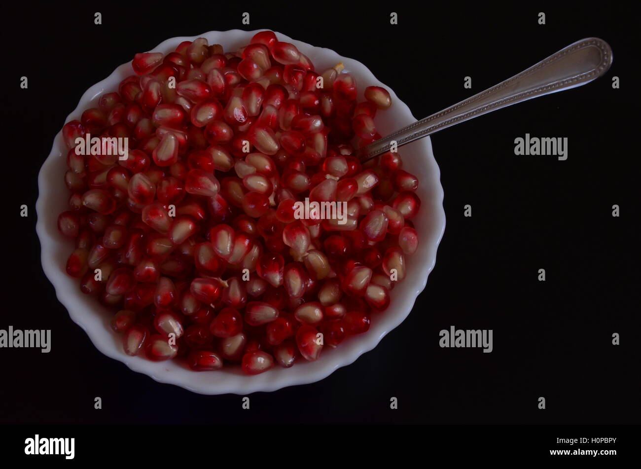 Bowl full of red juicy pomegranate pearls with a spoon and half ...