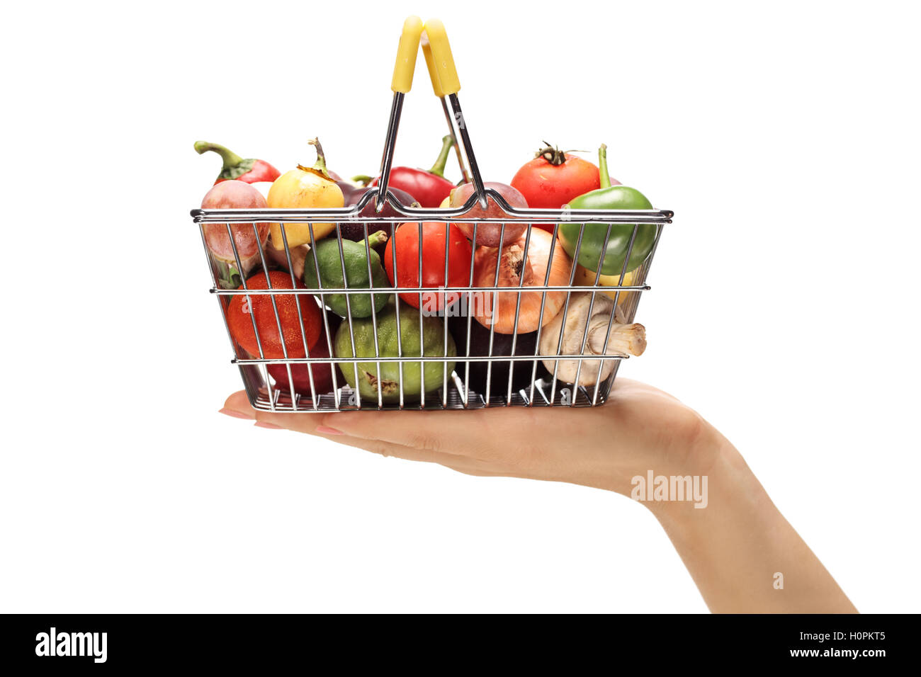 Close-up of a hand holding a small shopping basket full of vegetables ...