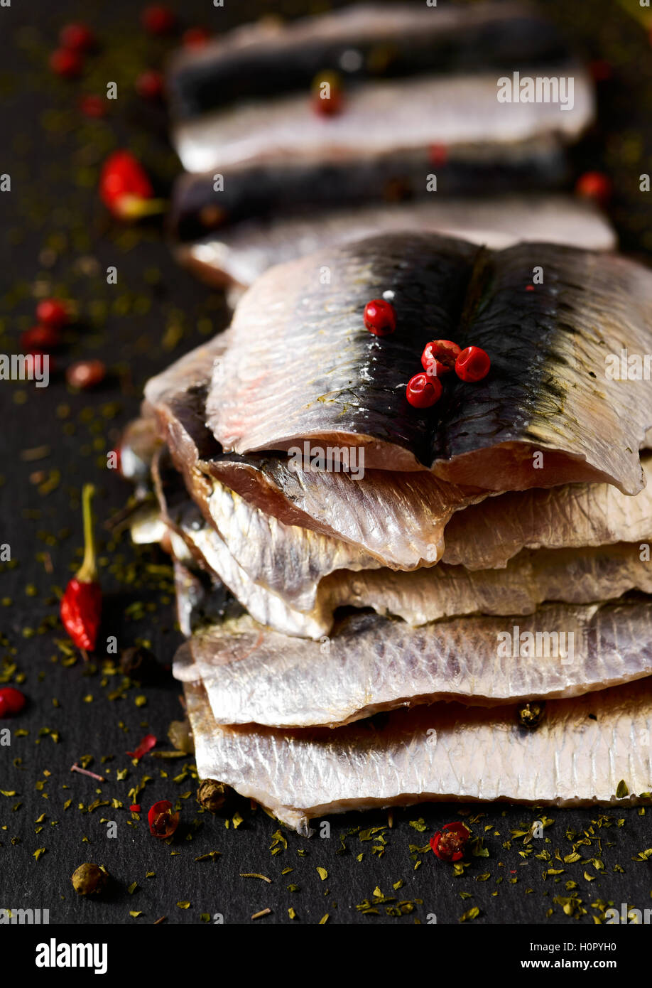 closeup of some raw sardine fillets on a slate surface, spiced with ...