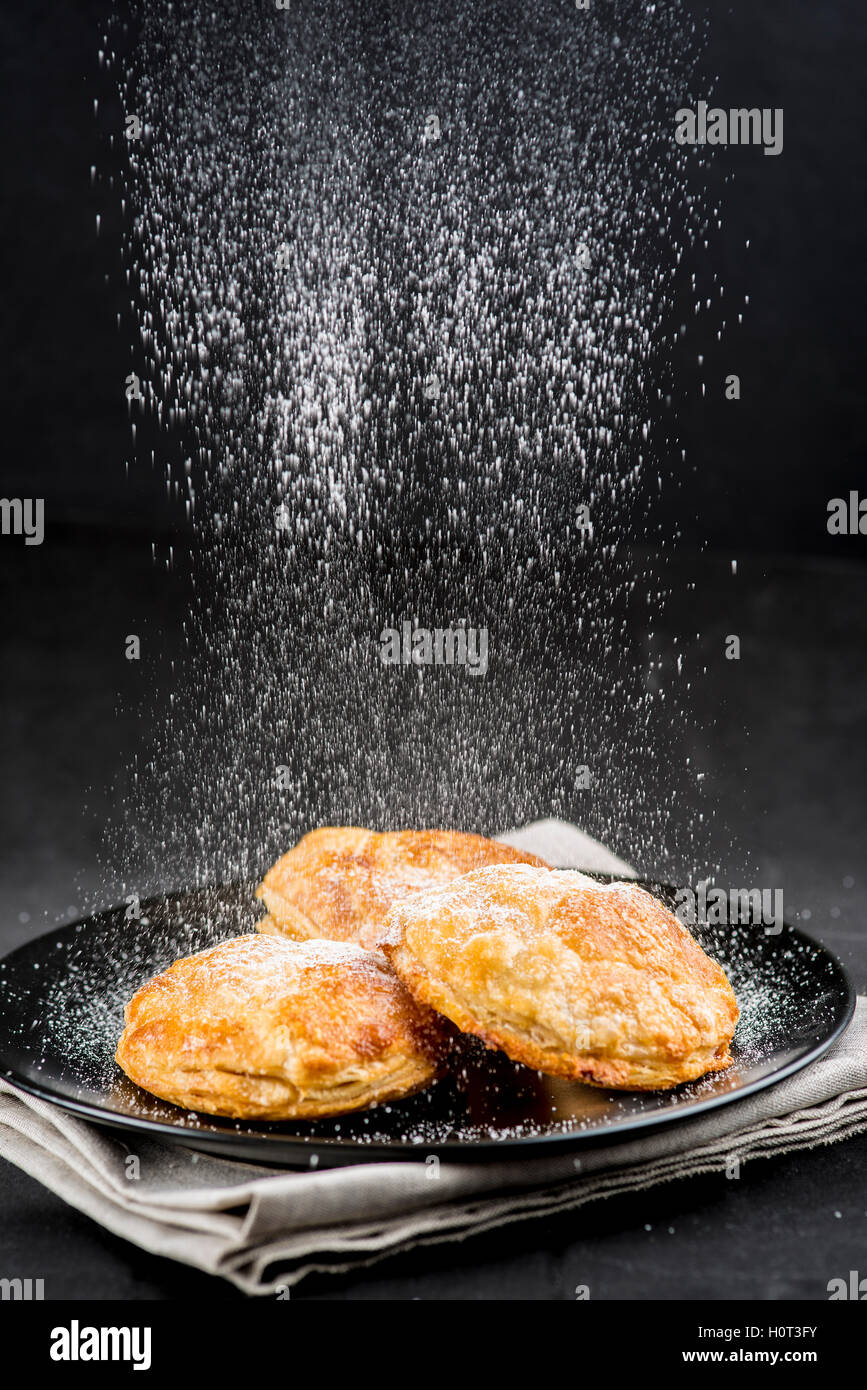 Sprinkling powdered sugar on cakes on a black background Stock Photo ...