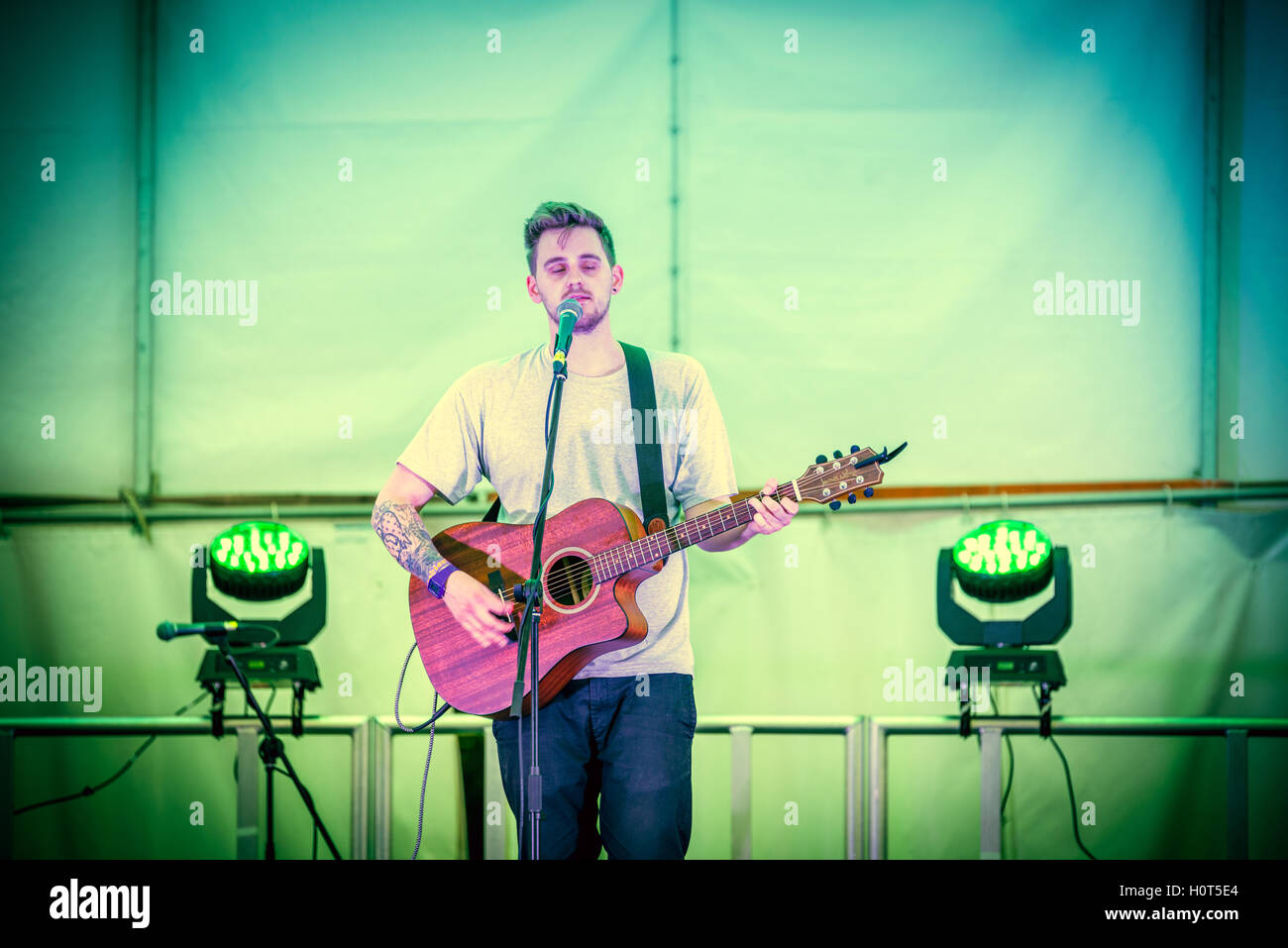 A man singing and playing guitar on stage Stock Photo - Alamy