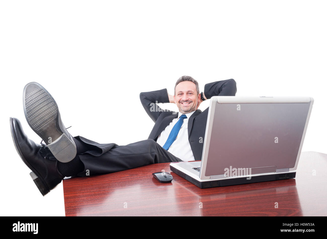 Smiling manager relaxing at the office with his shoes on the desk ...