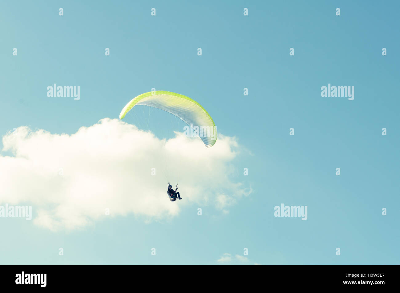 Paraglider with white wing turning around in the blue sky with copy ...