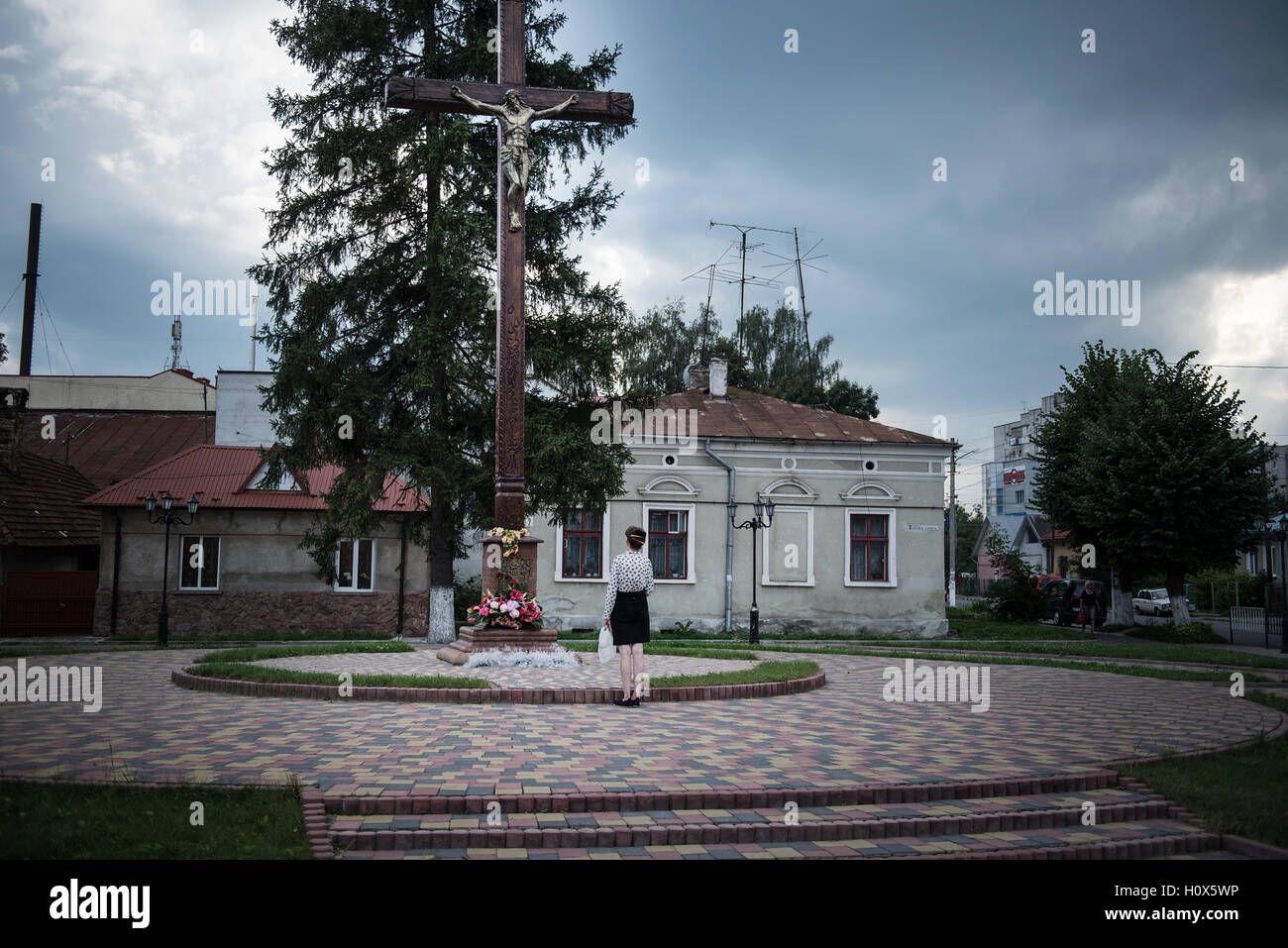 A woman prays under a cross, at the town of Stryi in western Ukraine ...