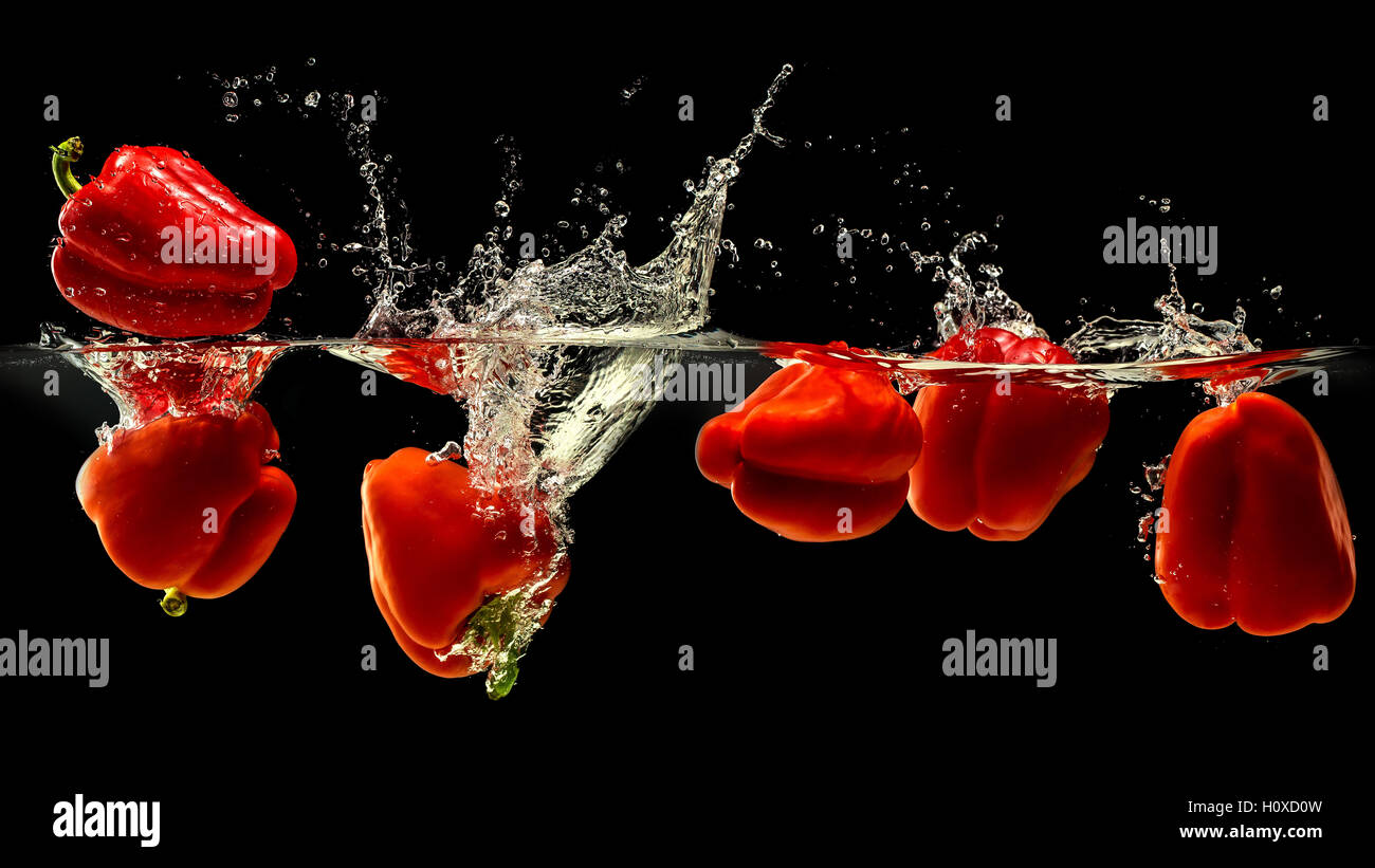 Group of bell pepper falling in water on black Stock Photo - Alamy