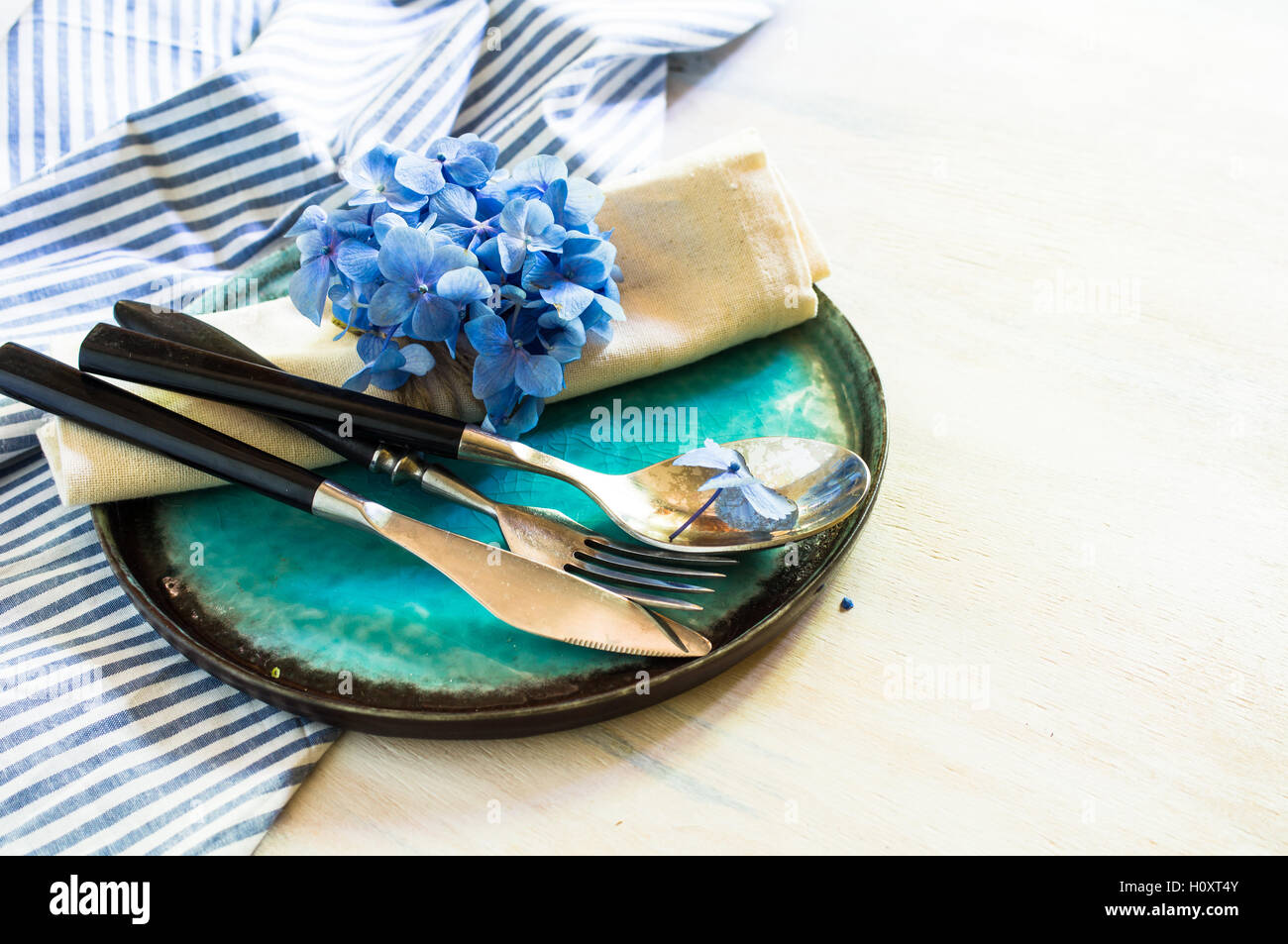 Vintage style table setting with fresh blue hydrangea flowers on rustic ...