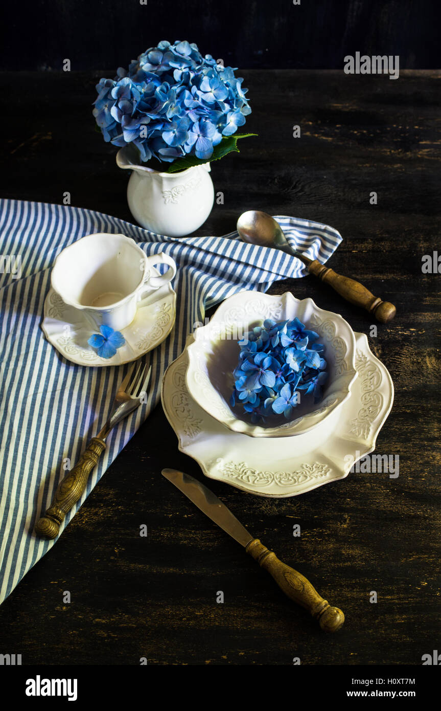 Vintage style table setting with fresh blue hydrangea flowers on rustic ...