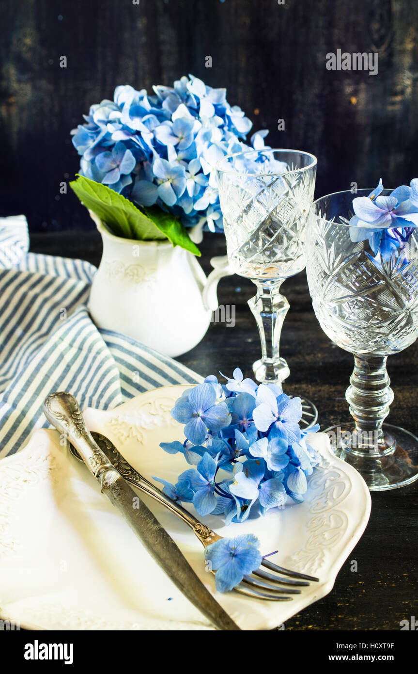 Vintage style table setting with fresh blue hydrangea flowers on rustic ...