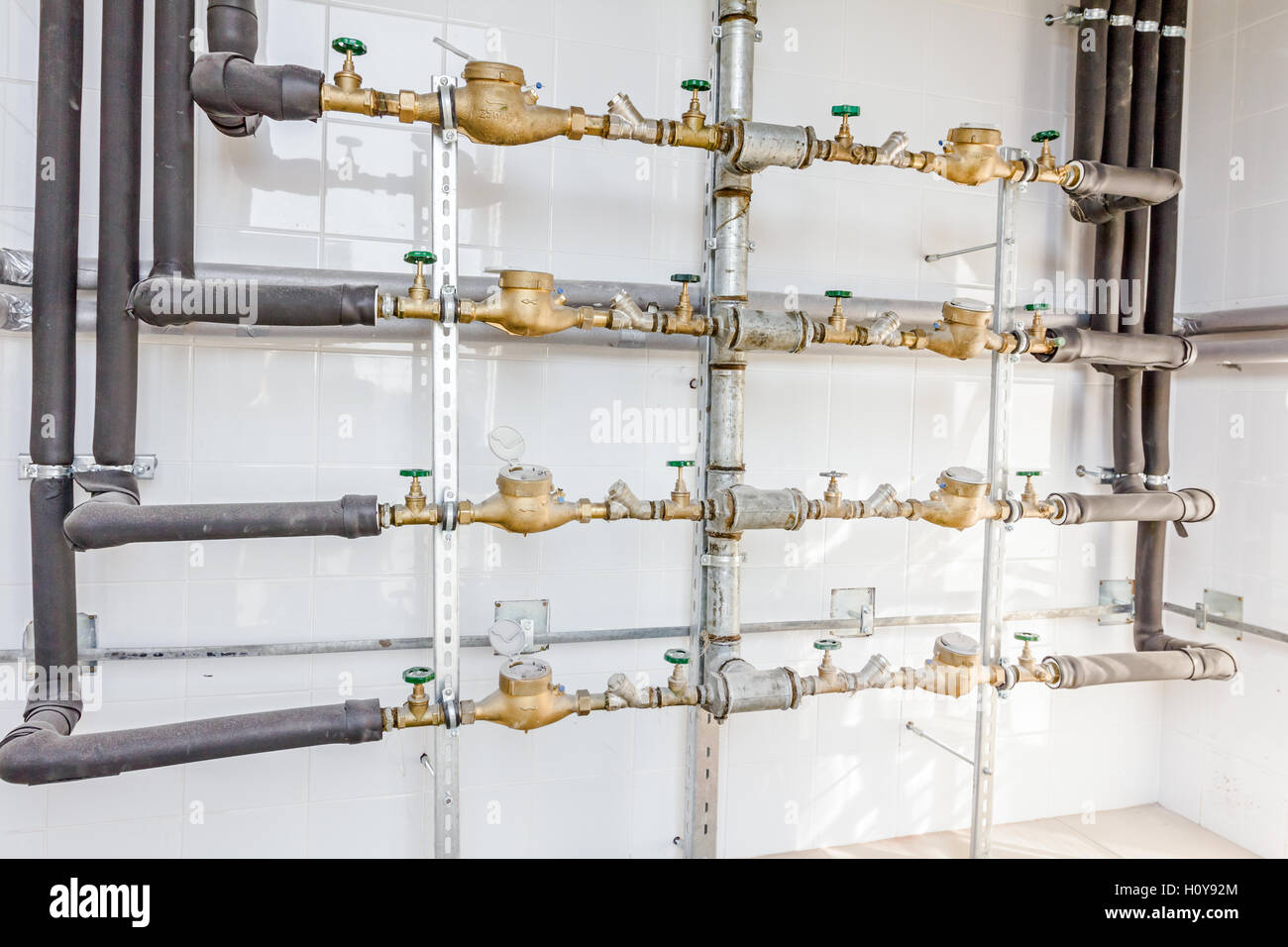 Water meters and valves in measuring place, tiled room with white tiles ...