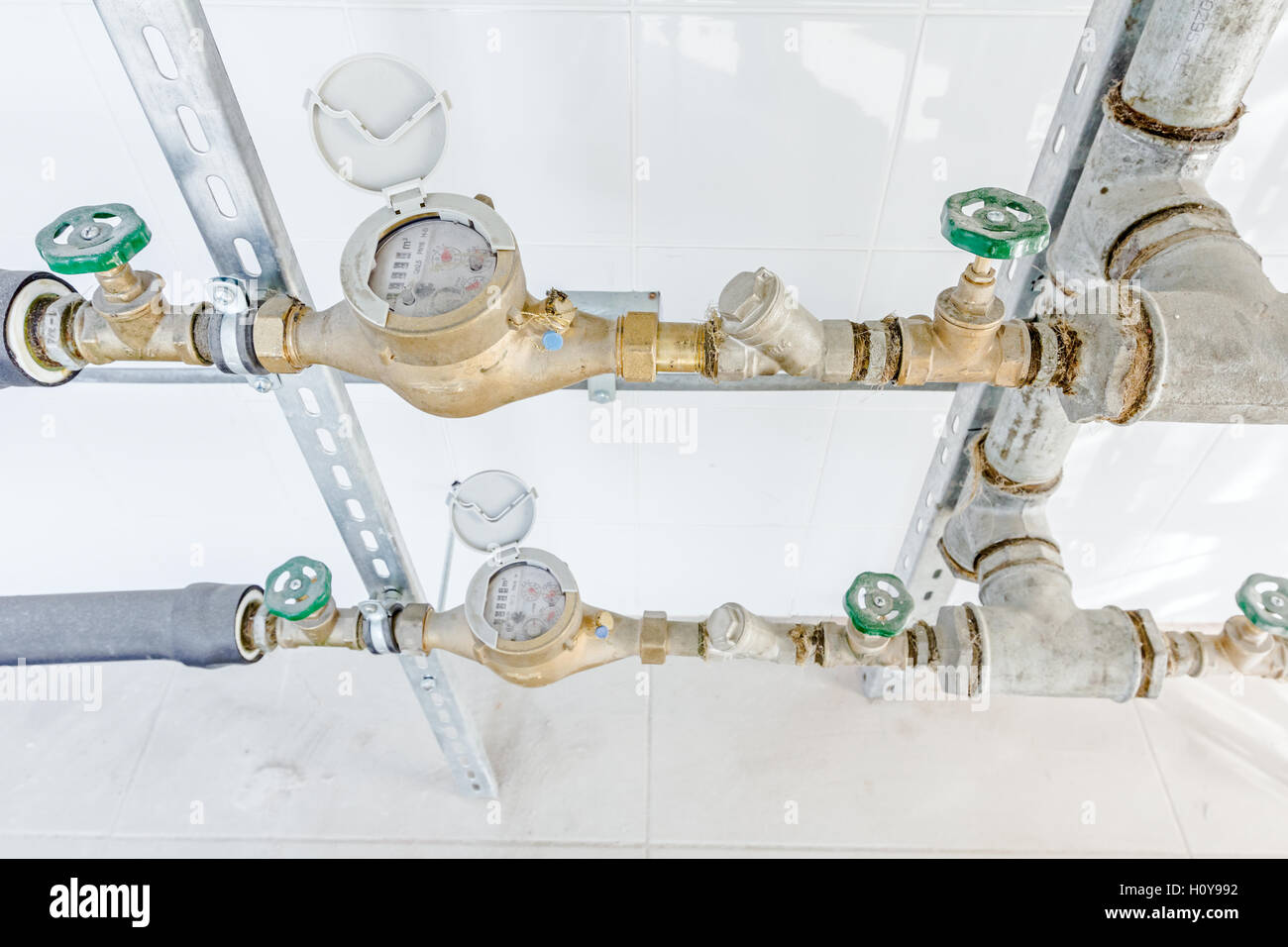 Water meters and valves in measuring place, tiled room with white tiles ...