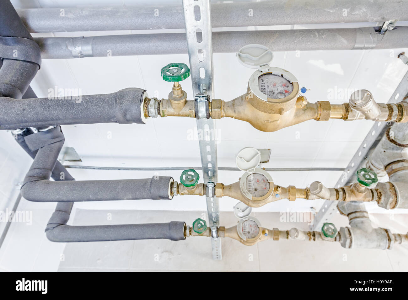 Water meters and valves in measuring place, tiled room with white tiles ...