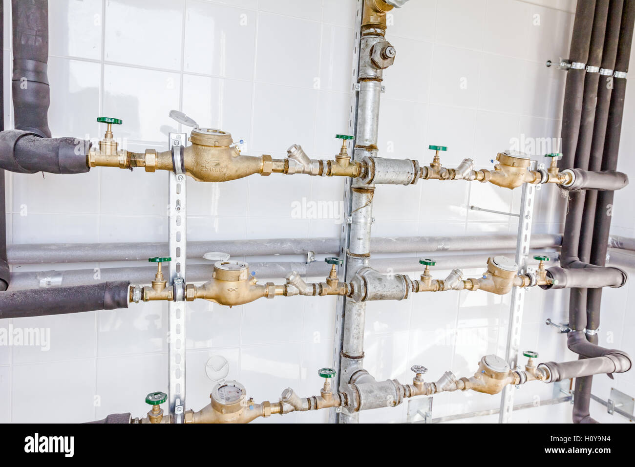 Water meters and valves in measuring place, tiled room with white tiles ...