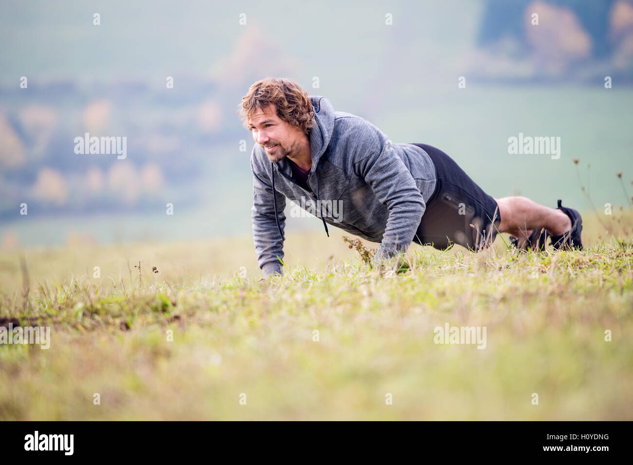 Handsome young runner doing push ups, autumn nature Stock Photo - Alamy