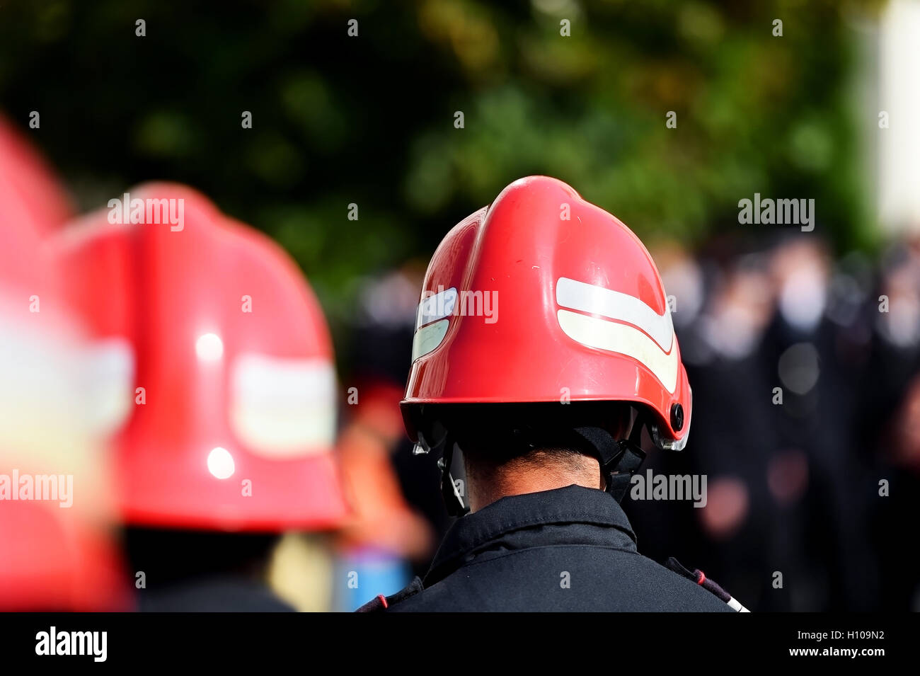 Firefighters wearing firefighter helmets are seen from behind during ...