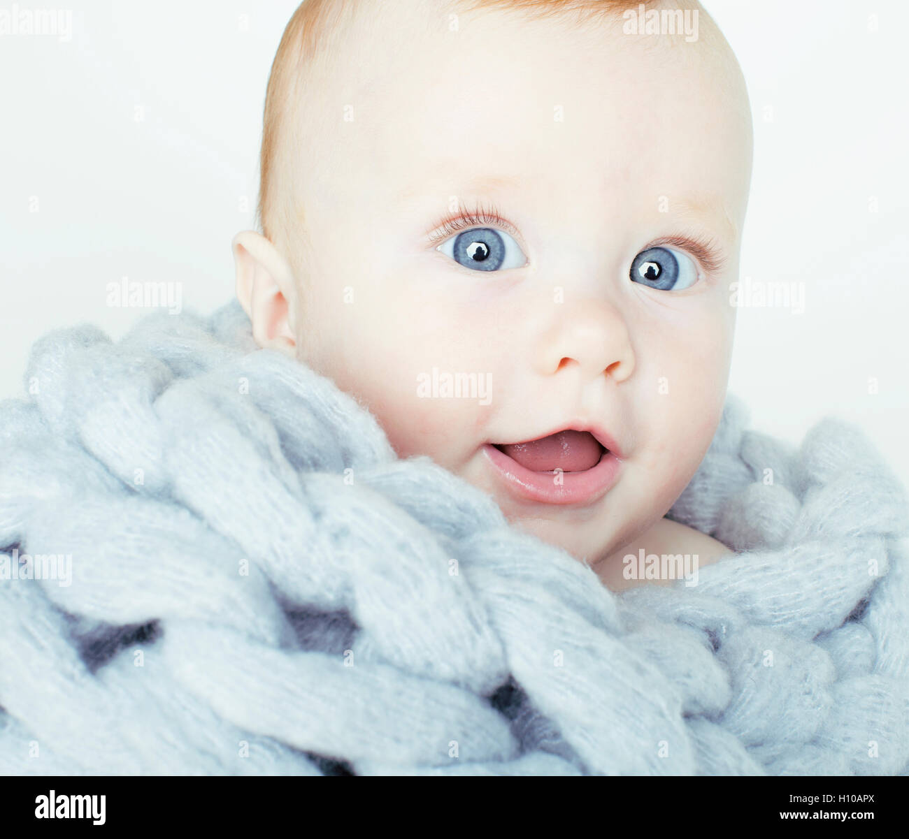 little cute red head baby in scarf all over him close up isolated ...