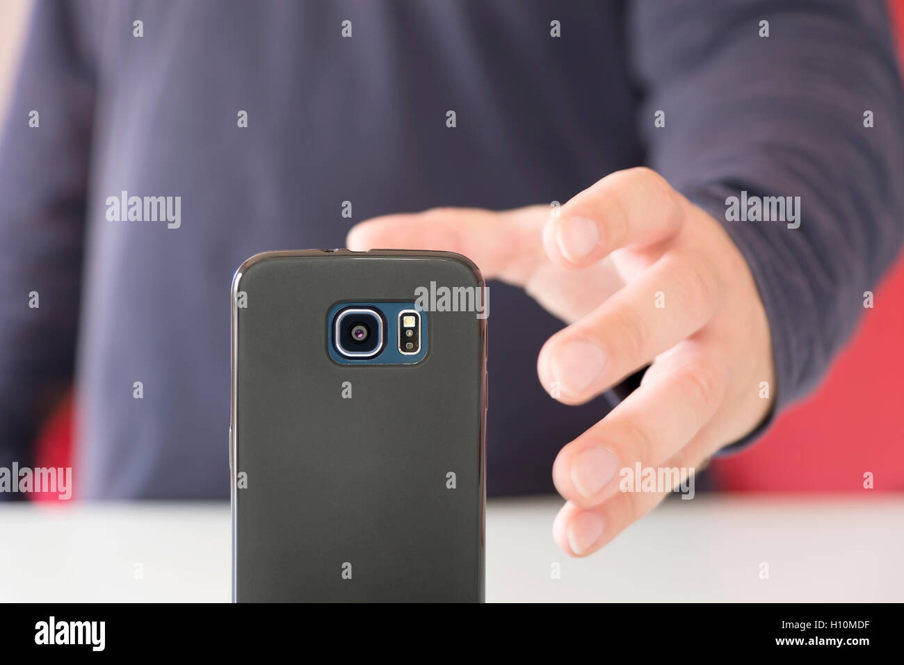 male hand reaching for a black smartphone Stock Photo - Alamy