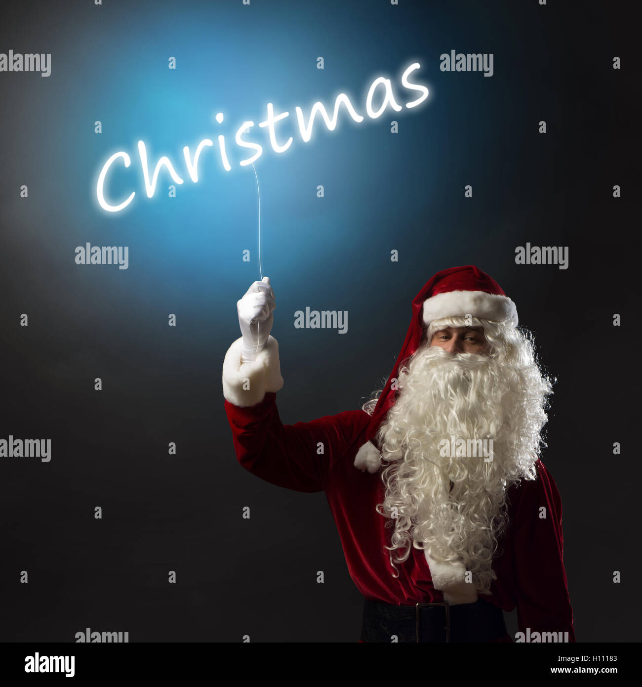 Santa Claus holding a light christmas word Stock Photo - Alamy