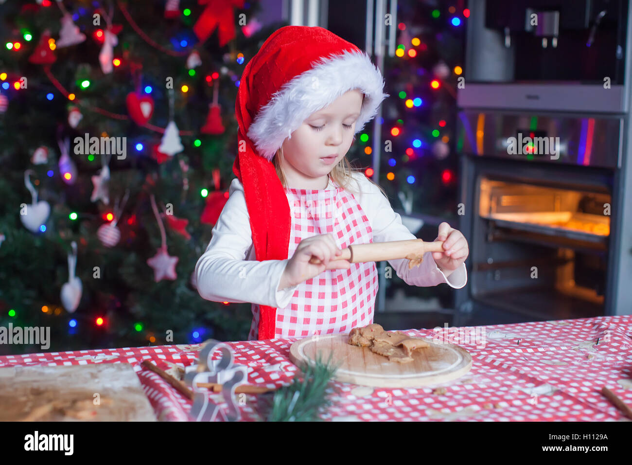 Adorable little girl in Santa hat baking gingerbread Christmas cookies ...
