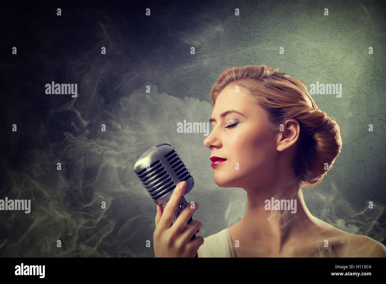 beautiful blonde woman singer with a microphone Stock Photo - Alamy