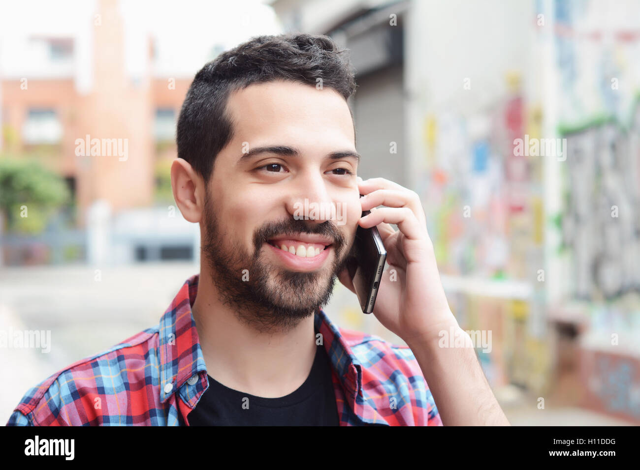 Handsome young latin man talking on the phone. Trendy and urban scene ...