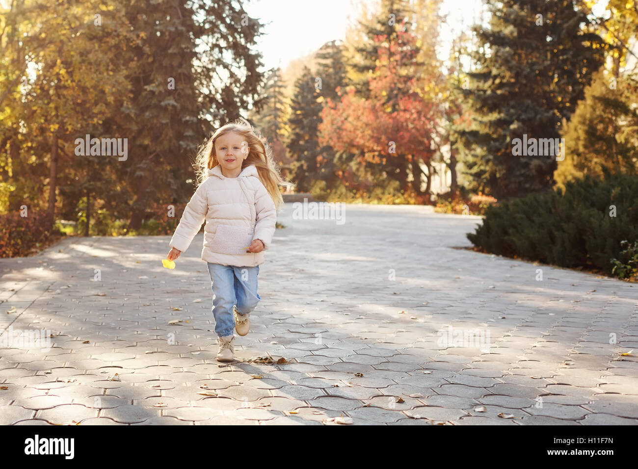 Little cute girl running in autumn park Stock Photo - Alamy