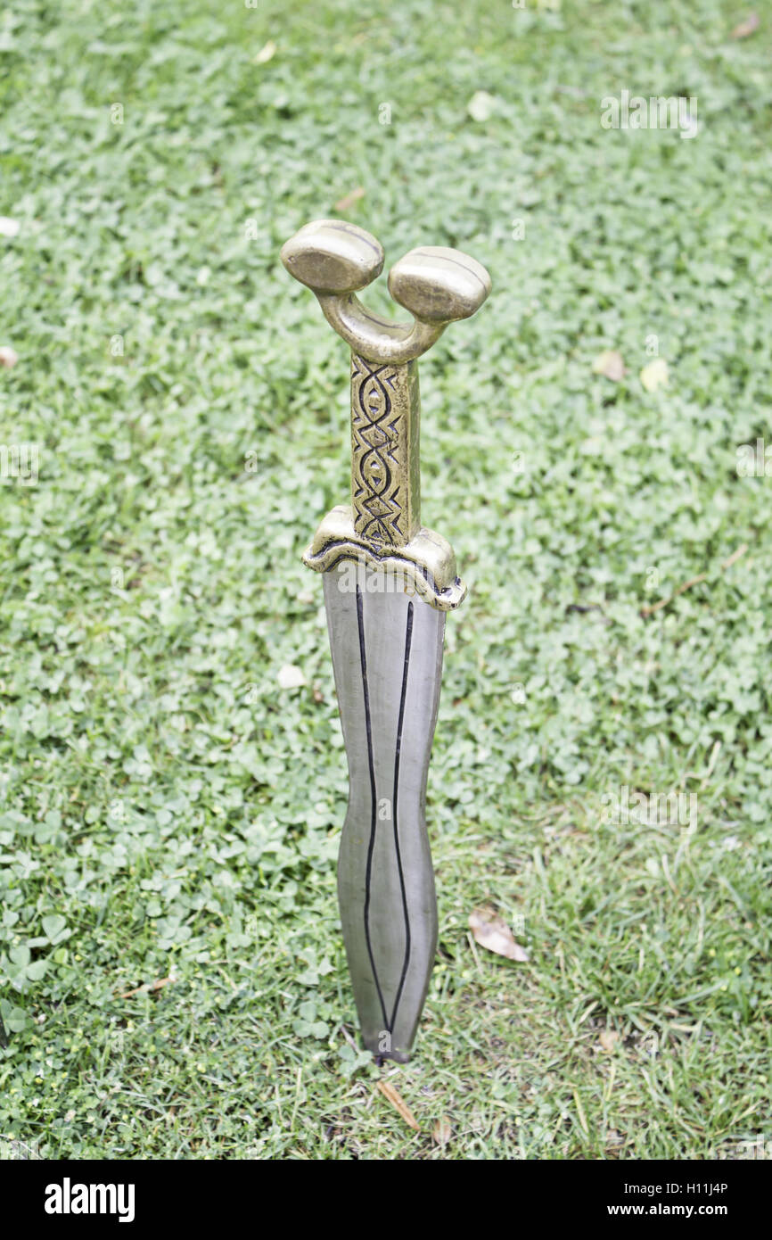 Medieval bronze sword stuck in the ground, object Stock Photo - Alamy