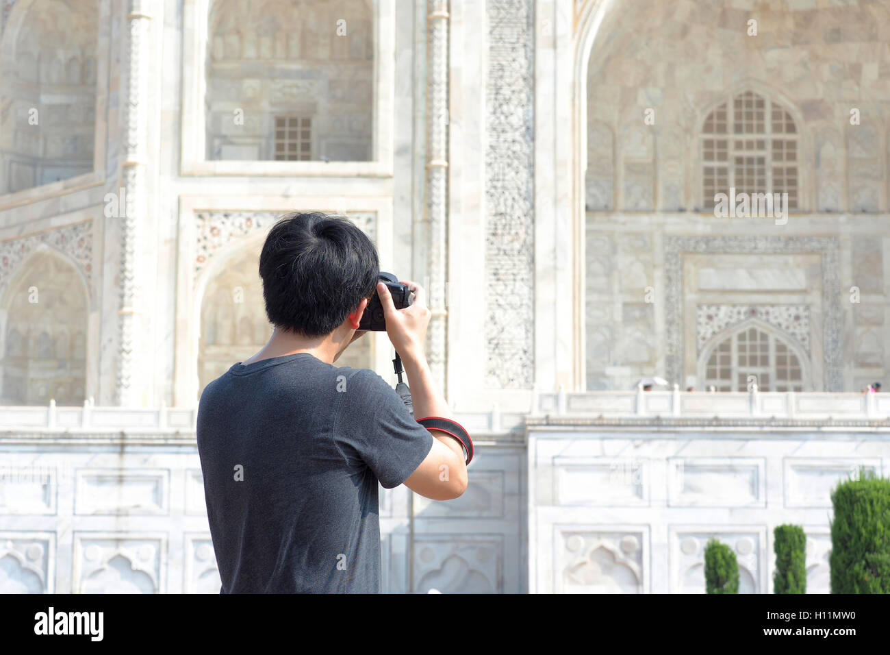 Close-up of Asian photographer on back taking pictures of Taj Mahal ...