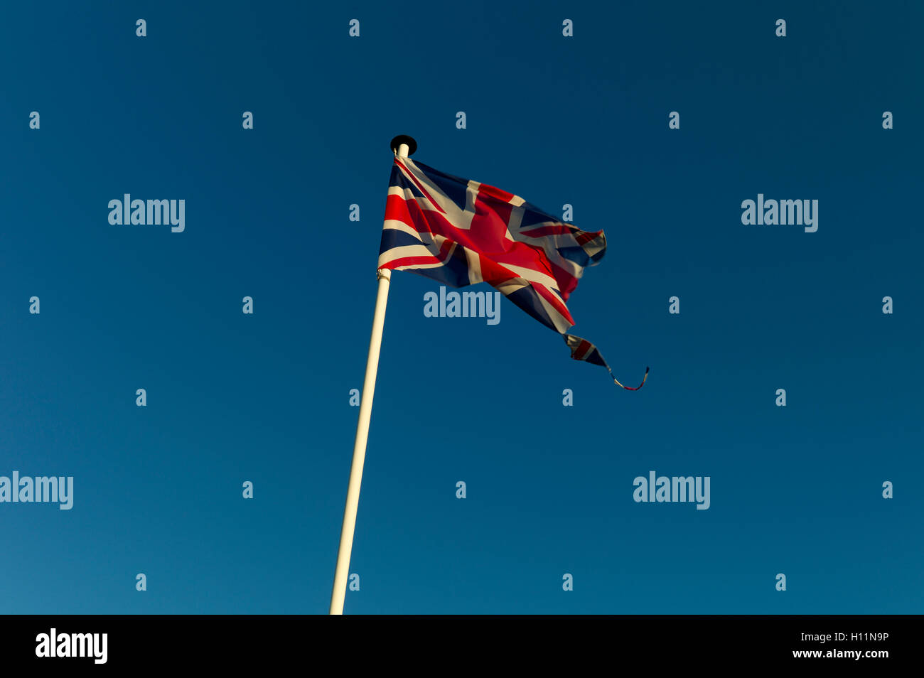 Tattered Union Jack flag against blue sky Stock Photo - Alamy