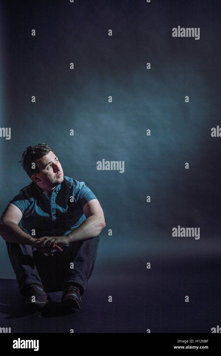 Young man looking lonely in a pool of light Stock Photo - Alamy