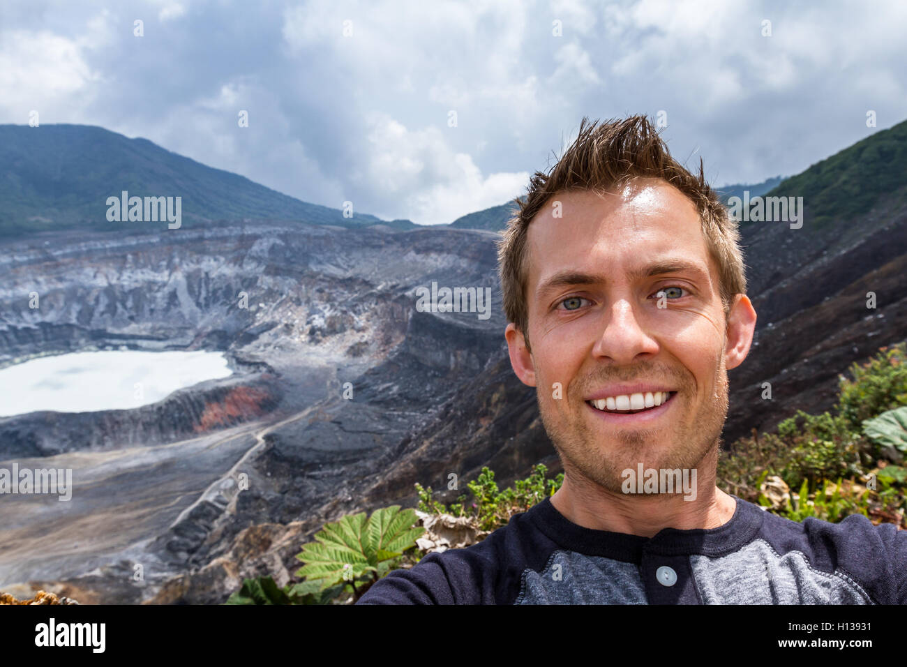 young male taking a self portrait with the Poas Volcano in the ...