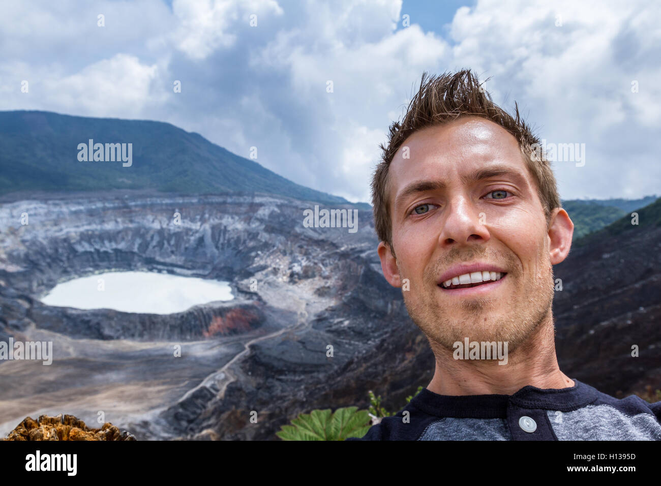 young male taking a self portrait with the Poas Volcano in the ...