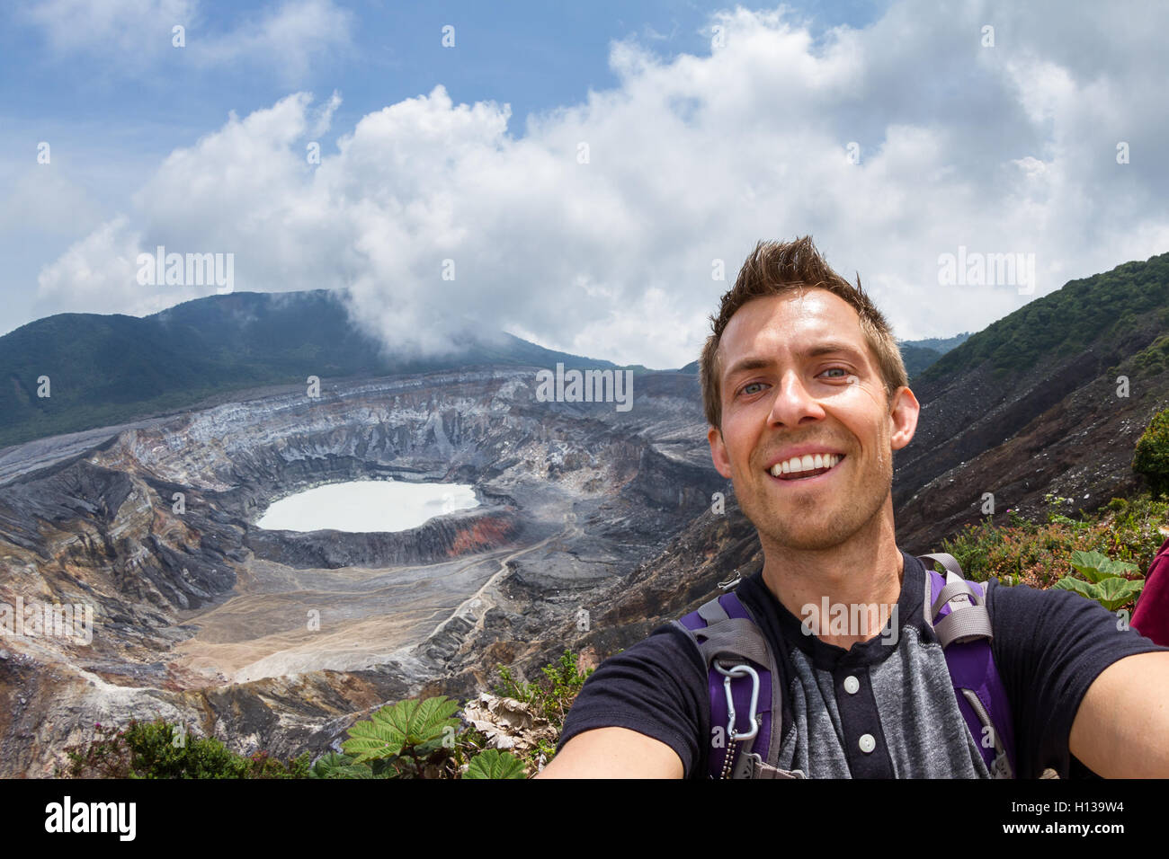 young male taking a self portrait with the Poas Volcano in the ...