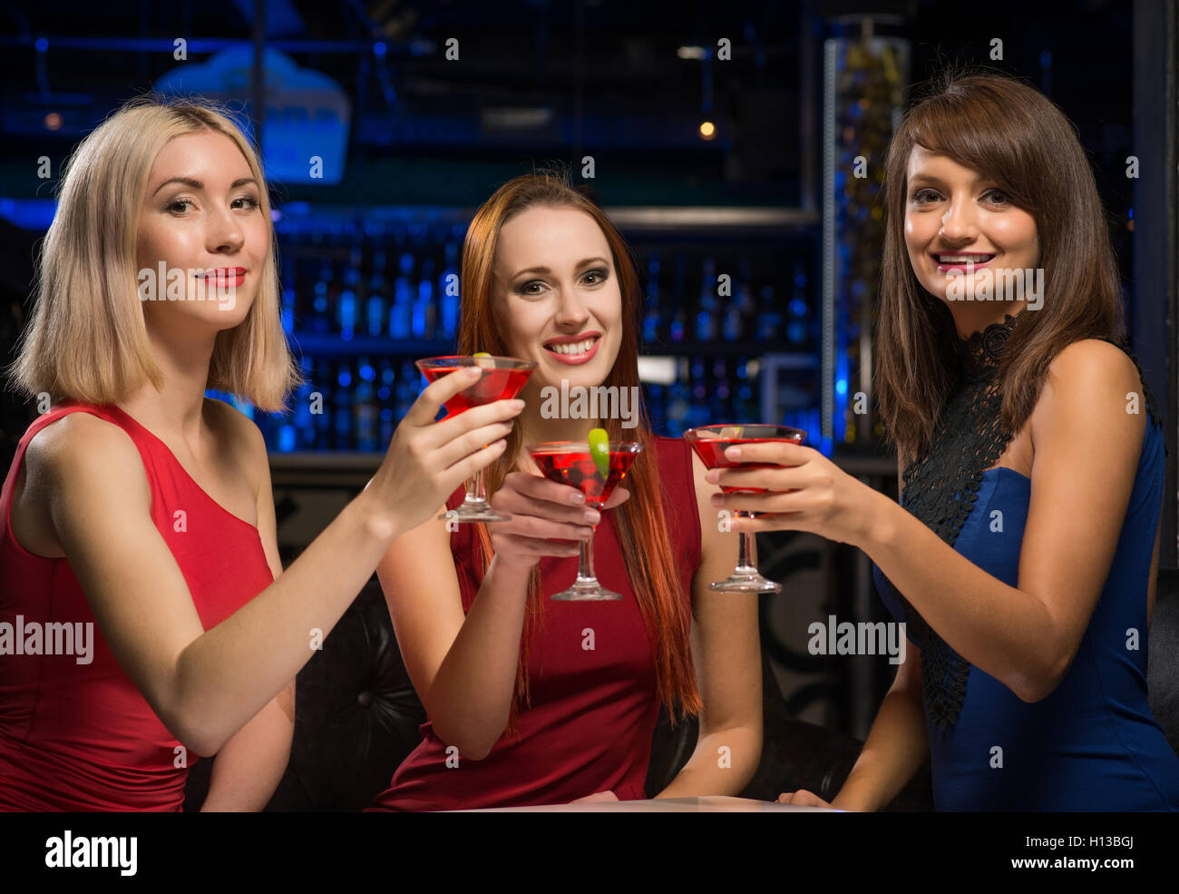 three girls raised their glasses in a nightclub Stock Photo - Alamy