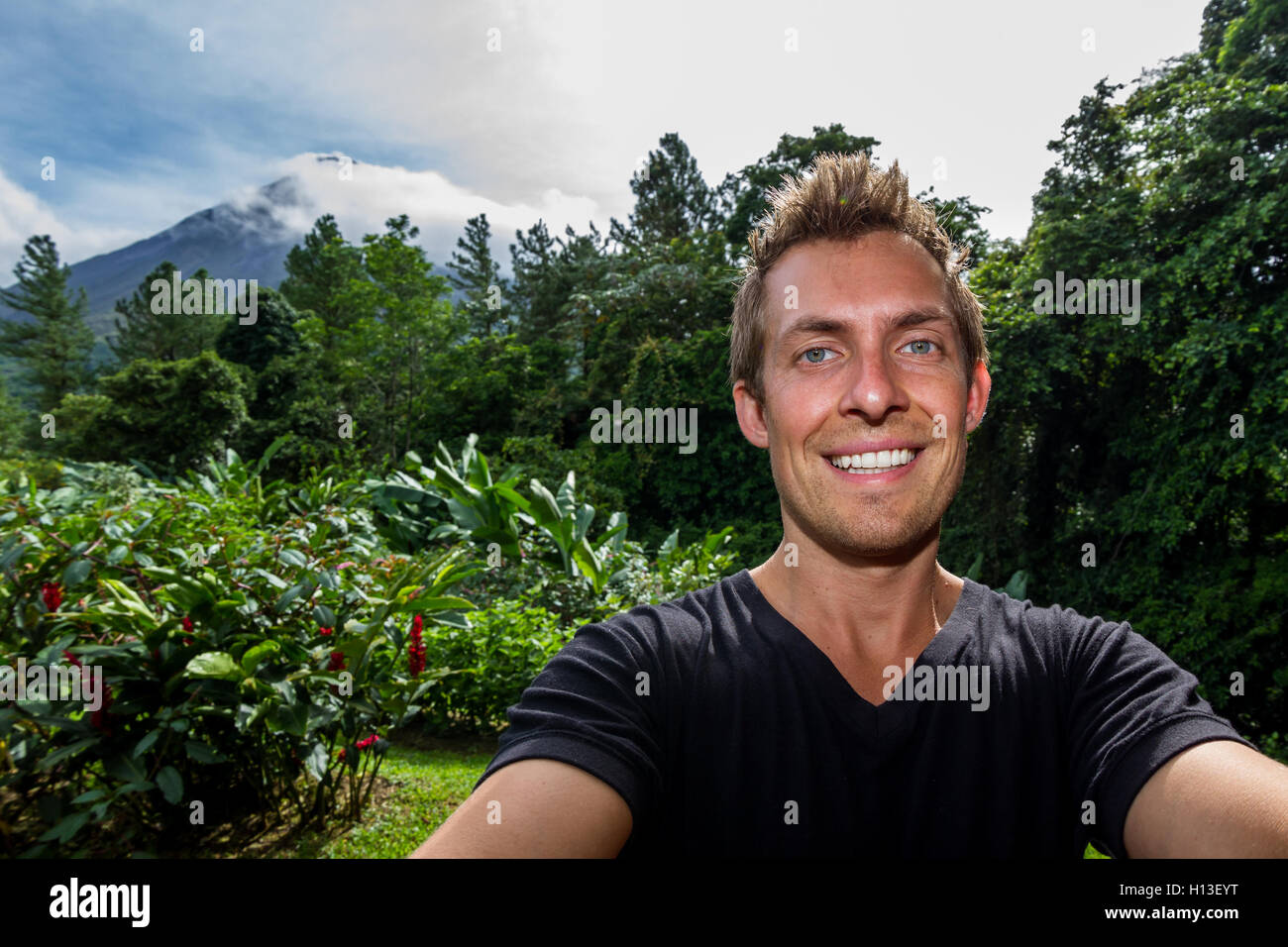 young man taking a self portrait with the famous Arenal Volcano in the ...