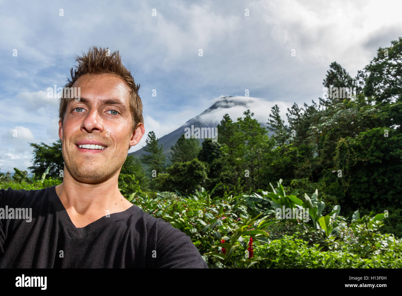 young man taking a self portrait with the famous Arenal Volcano in the ...