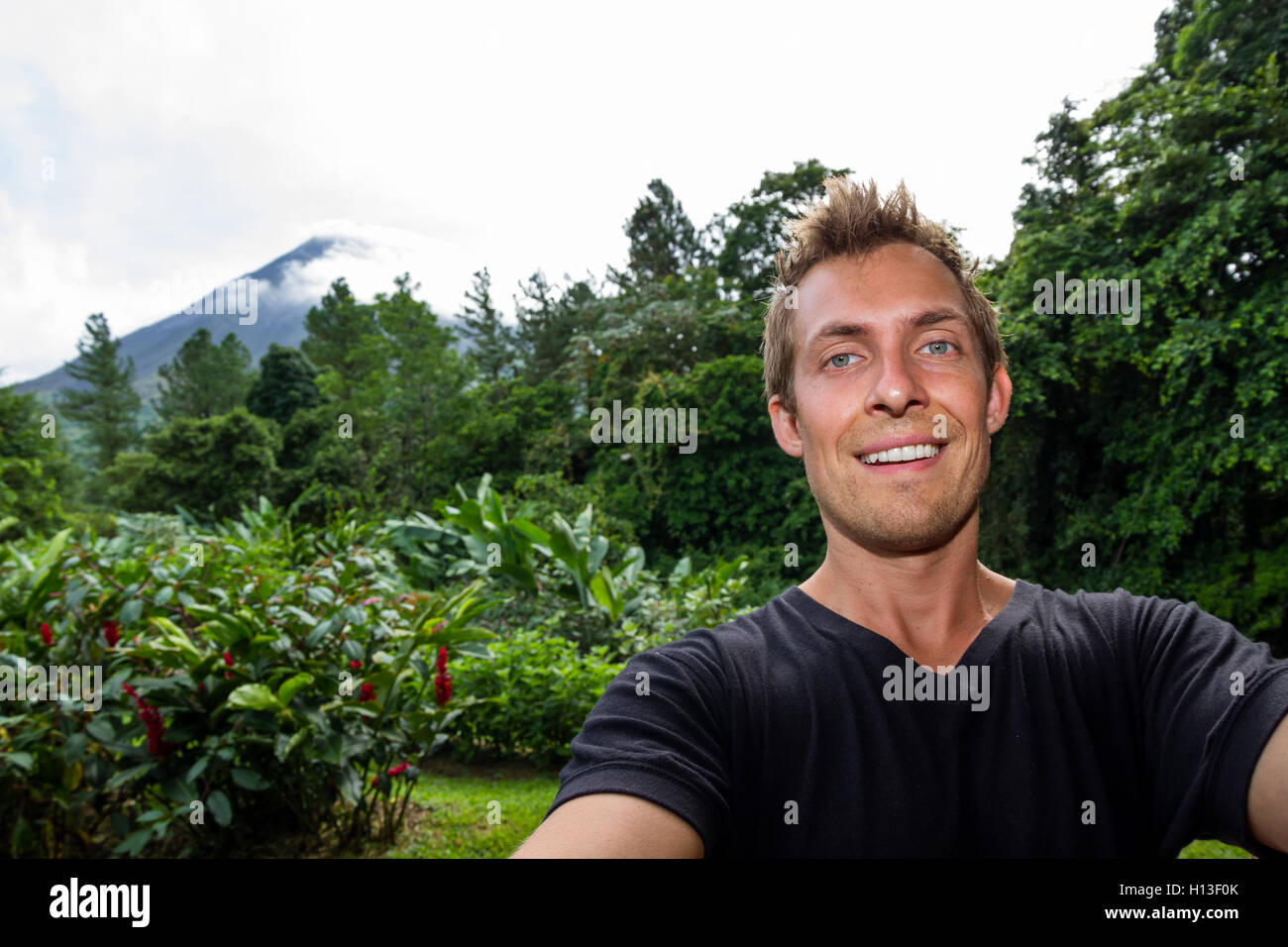 young man taking a self portrait with the famous Arenal Volcano in the ...