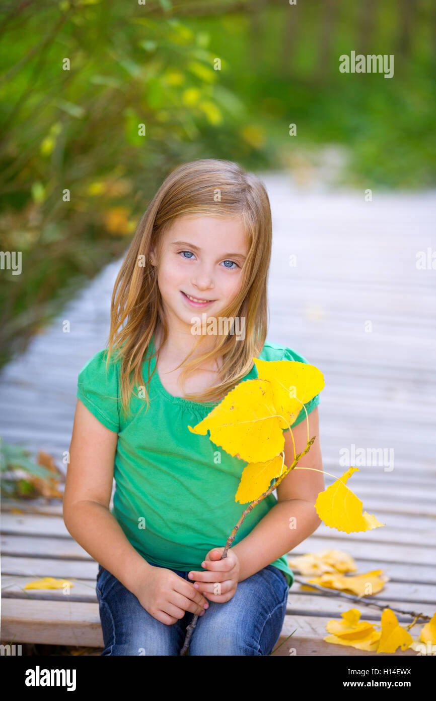 Kid girl in autumn wood deck with yellow leaves outdoor Stock Photo - Alamy