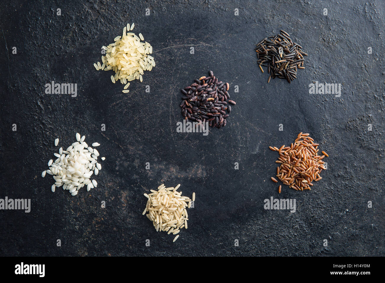 Different rice varieties on old table. Top view Stock Photo - Alamy