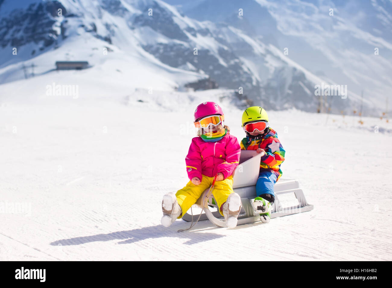 Little girl and baby boy play with snow on sleigh ride in Swiss Alps ...