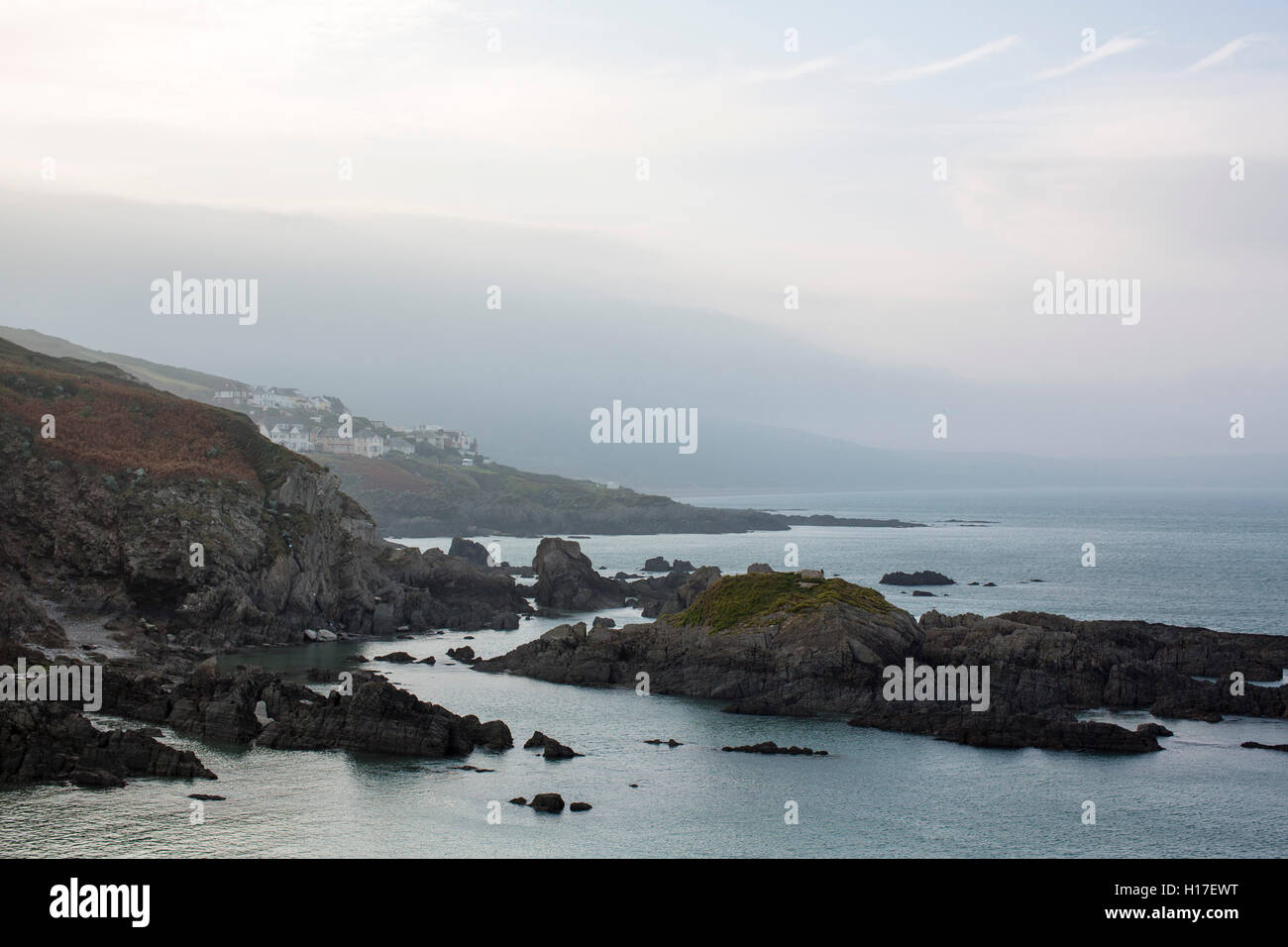 Grey misty coastline with rocks and houses on the south coast of the uk ...