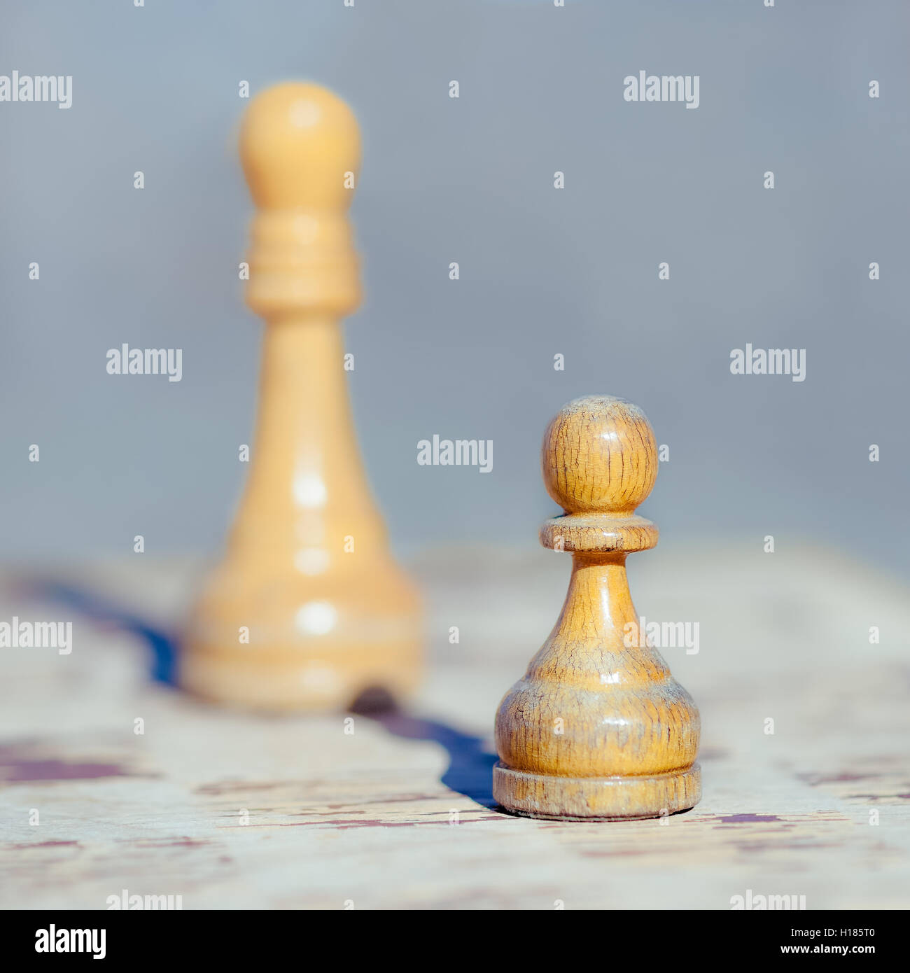 Old, used, weathered, chess pawn on a well worn chess board against the ...