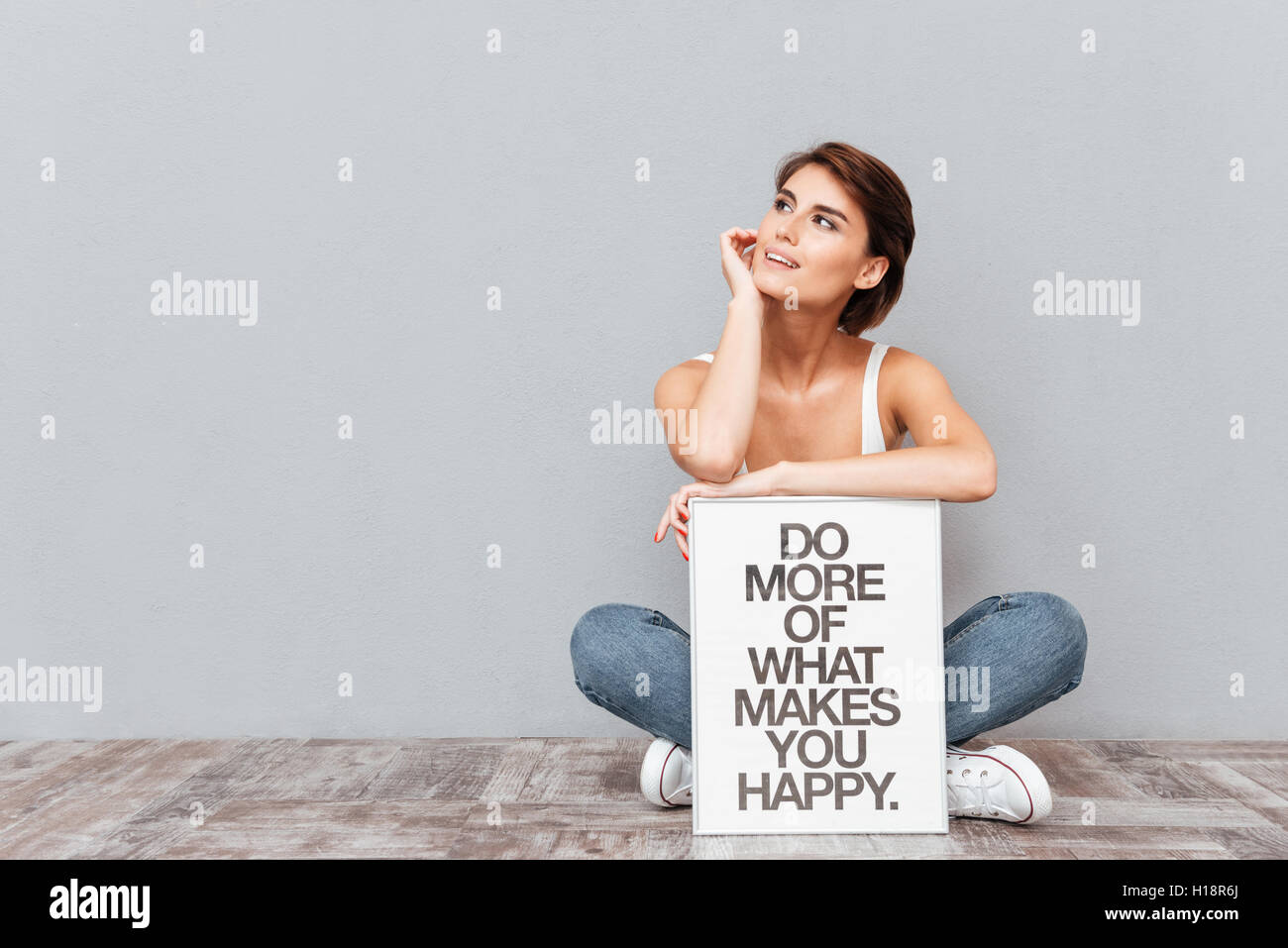 Smiling woman sitting on the floor and holding board with motivational ...