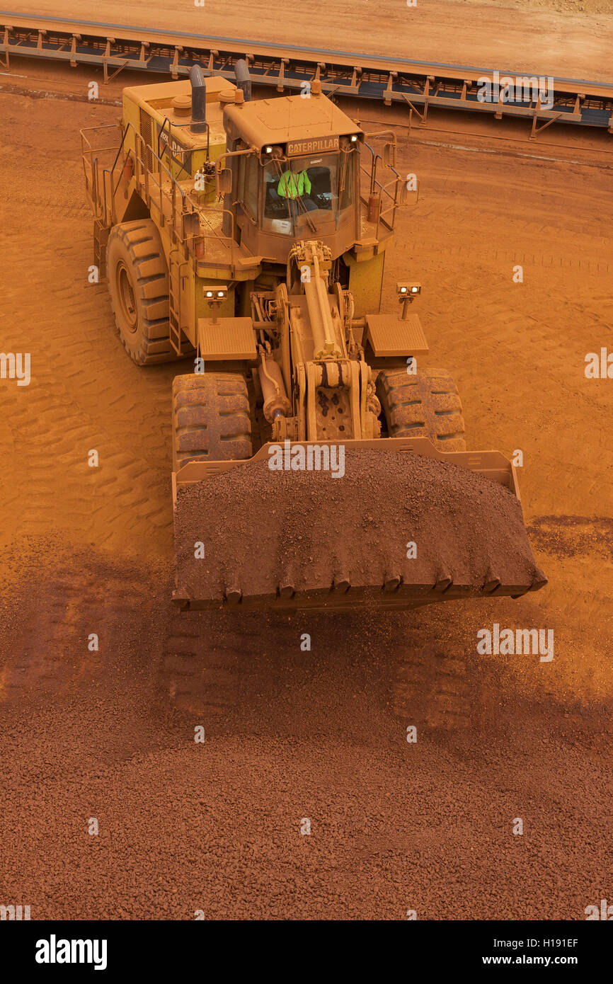 Front end loader loading hopper with lump iron ore from reclaimed stack ...