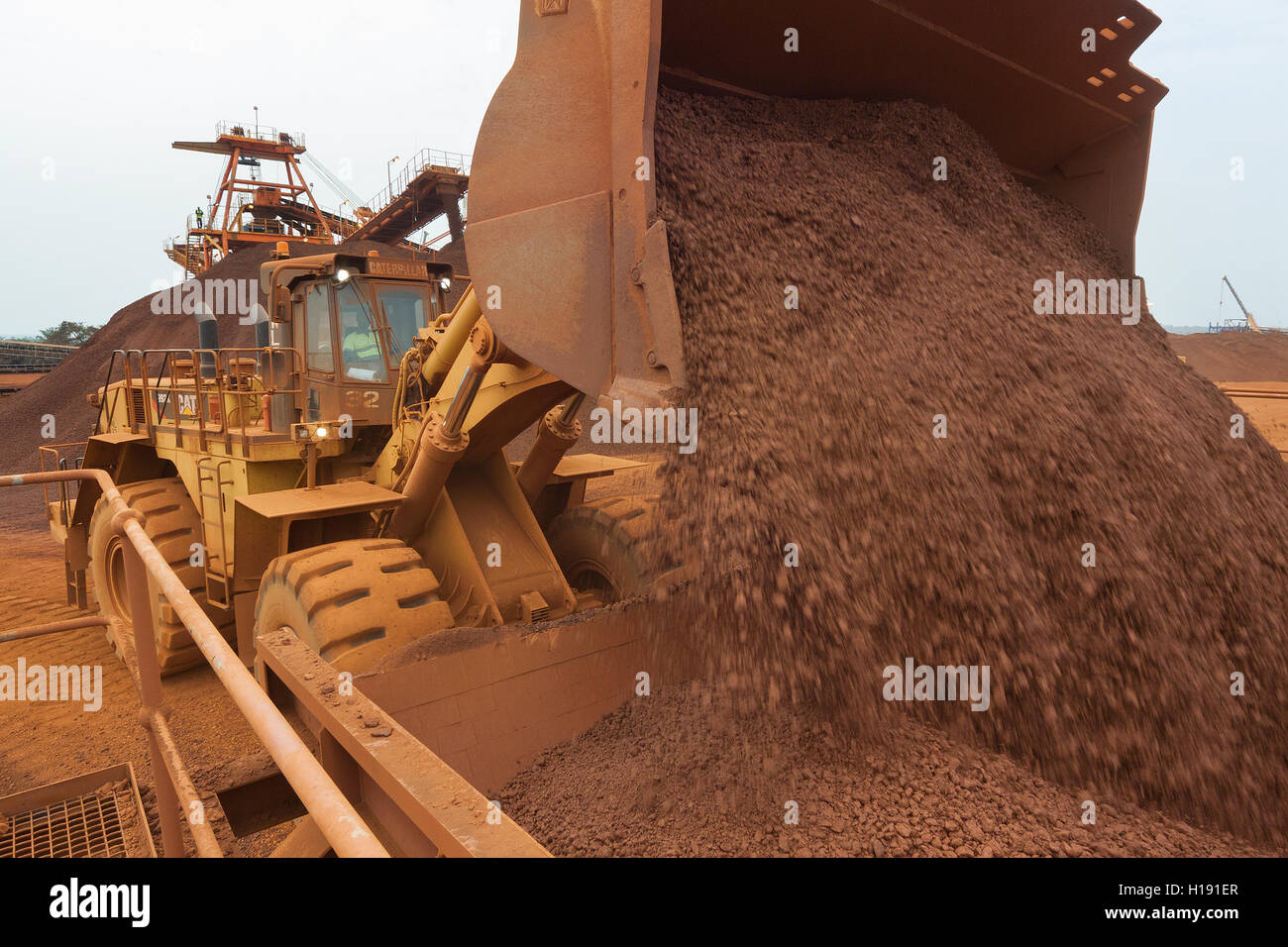 Front end loader loading hopper with lump iron ore from reclaimed stack ...