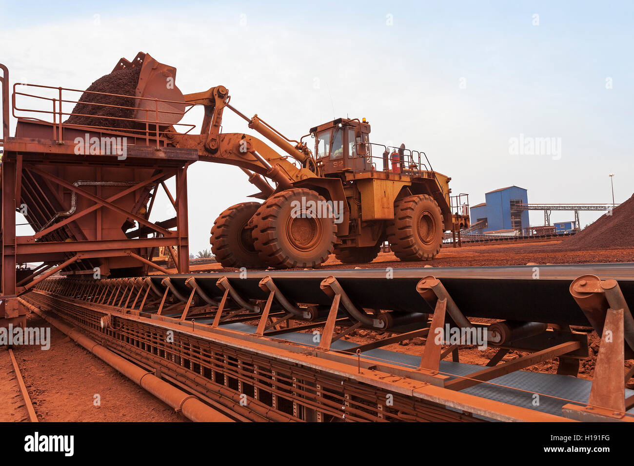 Front end loader loading hopper with lump iron ore from reclaimed stack ...