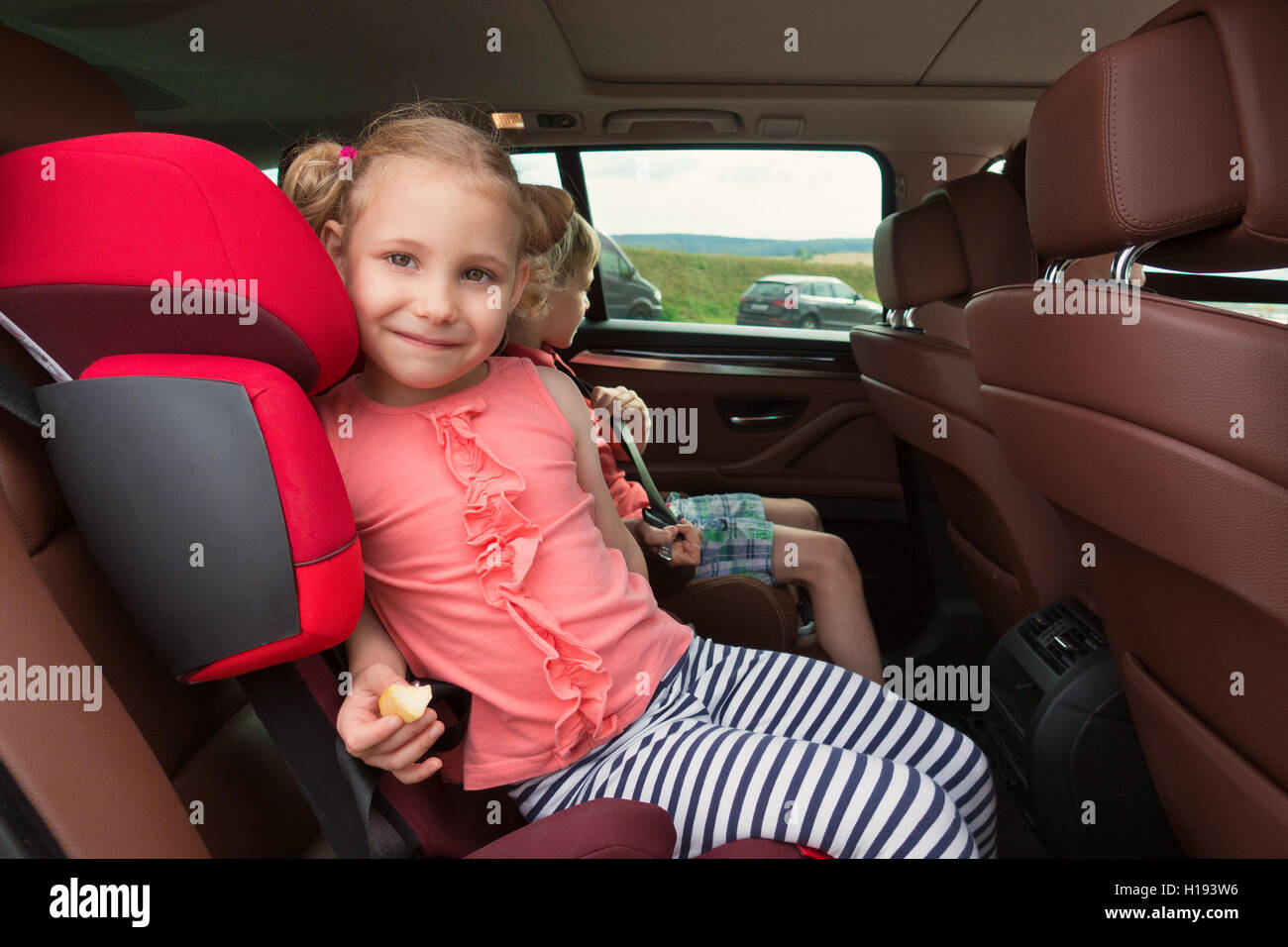 Portrait of happy little child girl sitting comfortable in car seat ...