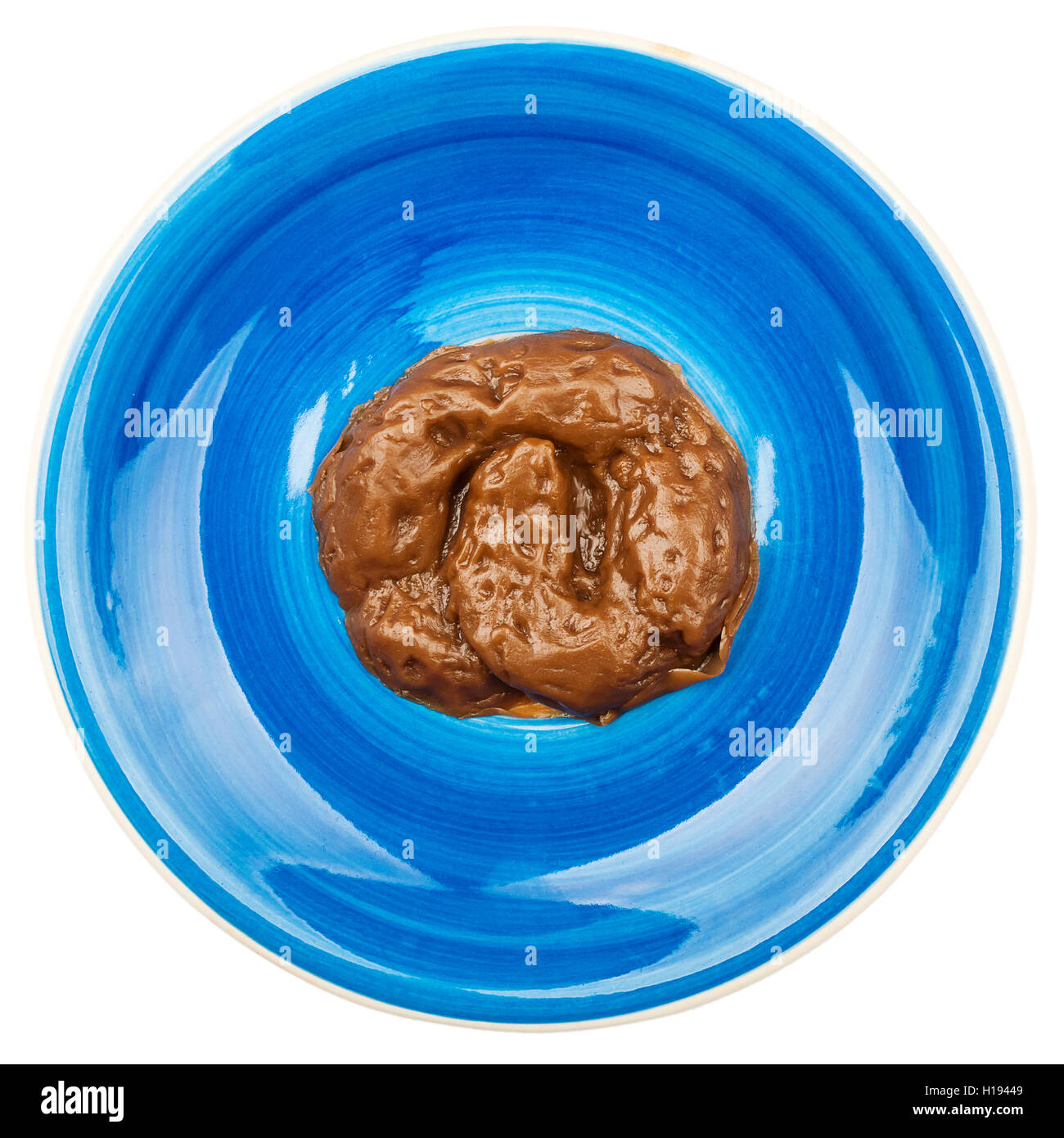 Fake rubber excrement in a blue plate isolated on white background ...