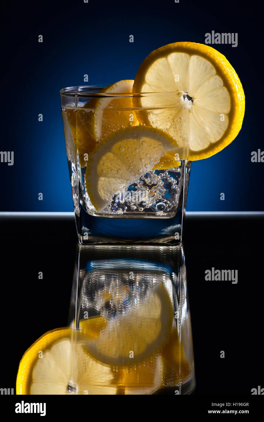 Gin with tonic; ice and lemon on a reflective background Stock Photo ...