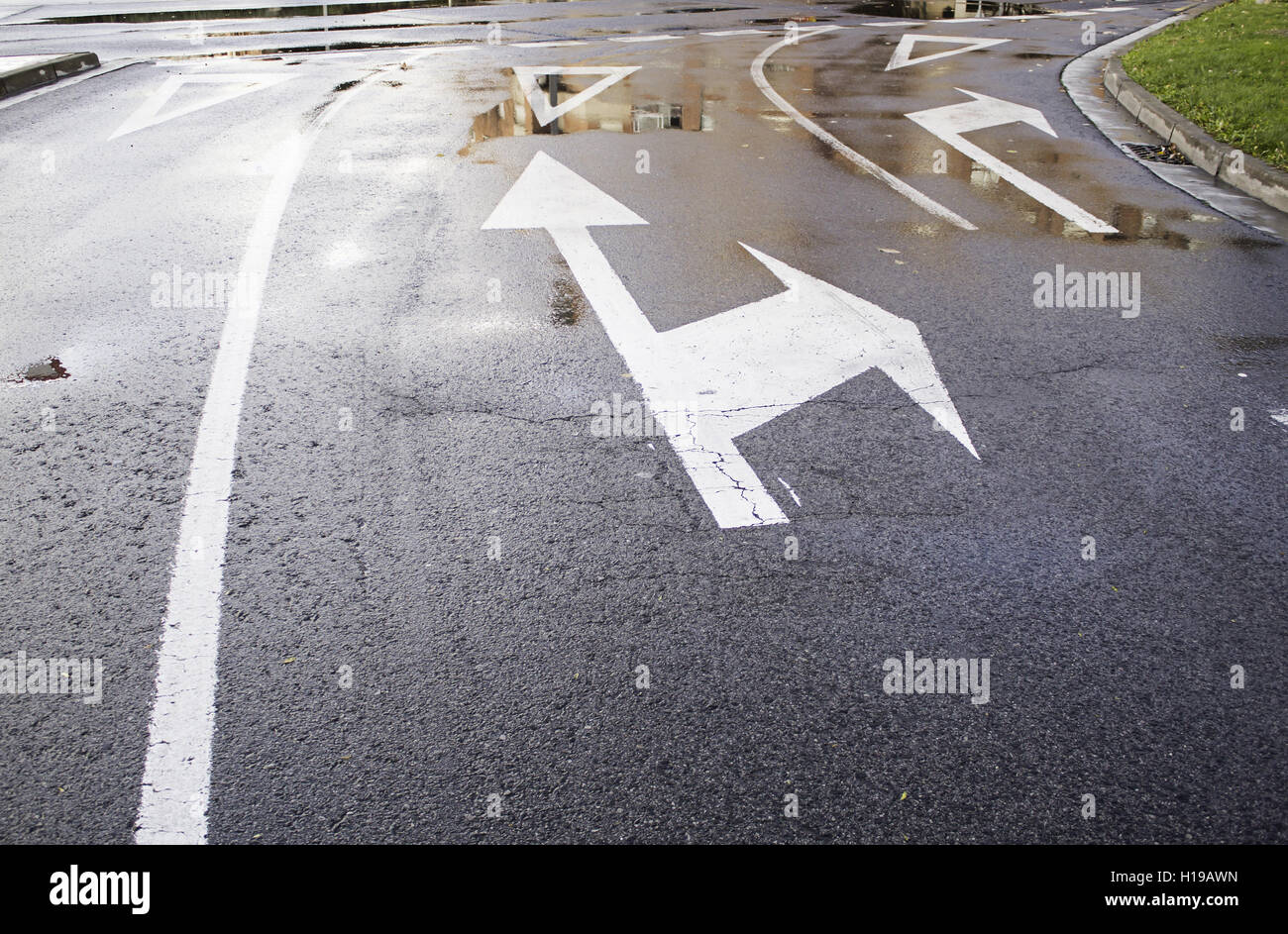 Urban wet road with direction arrow sign Stock Photo - Alamy