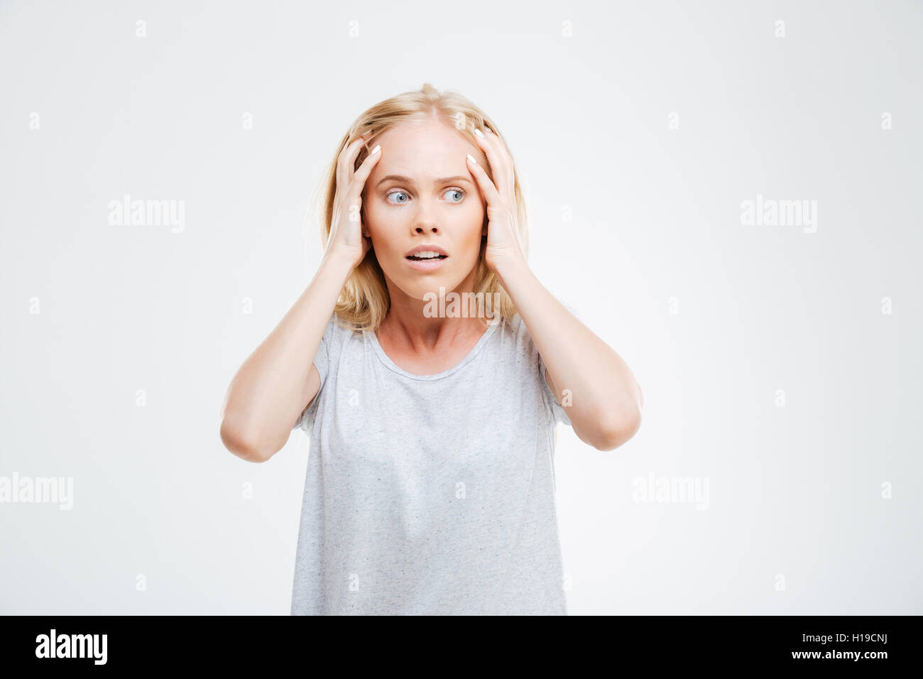Stressed confused blonde woman standing isolated on a white background ...
